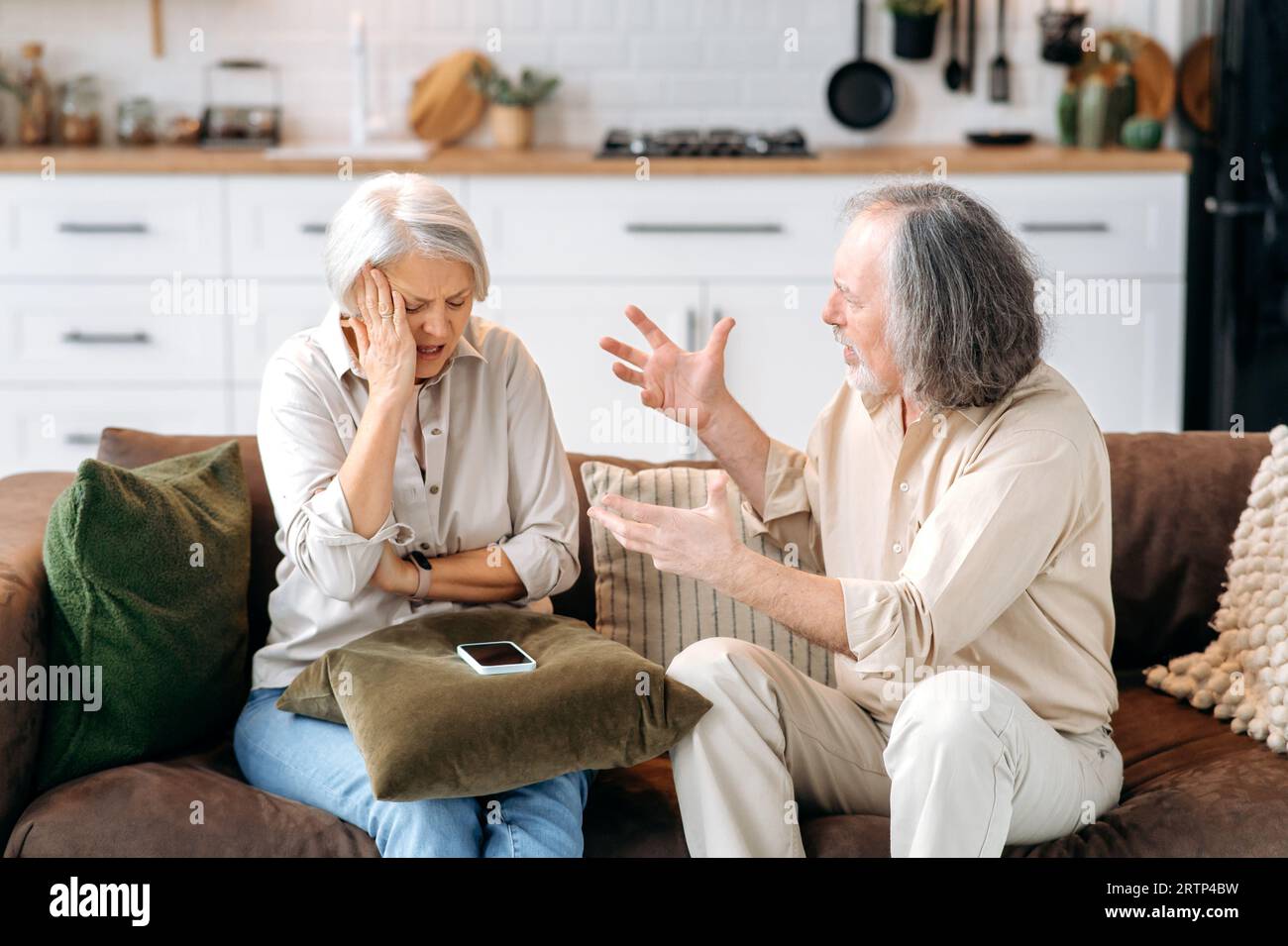 Mature caucasian couple, pensioners, sit on the sofa in the living room ...