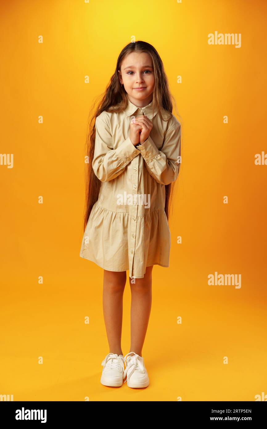 Little girl begging looking at viewer against yellow backgorund in ...