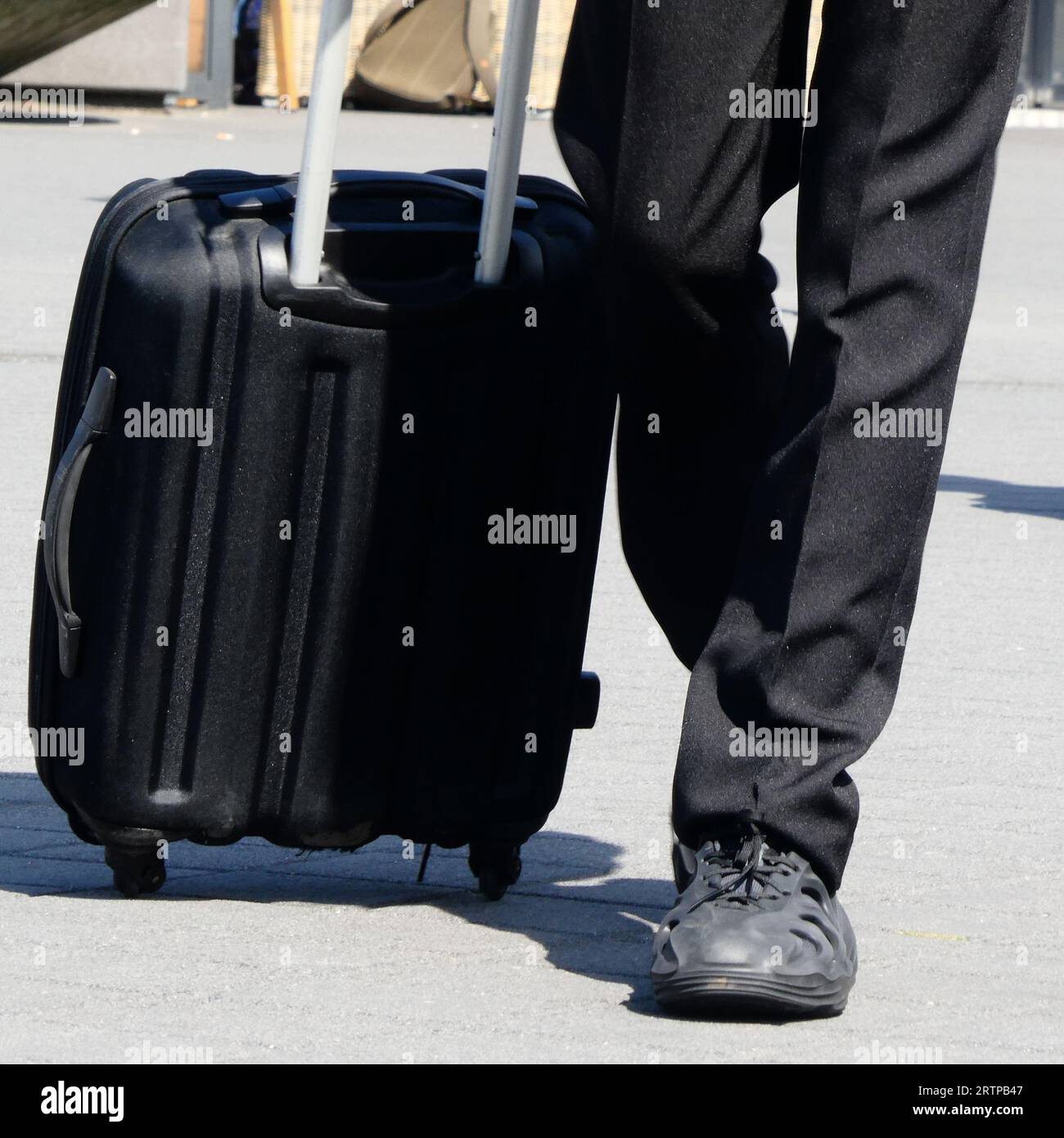 The legs of a man pulling his trolley suitcase Stock Photo - Alamy