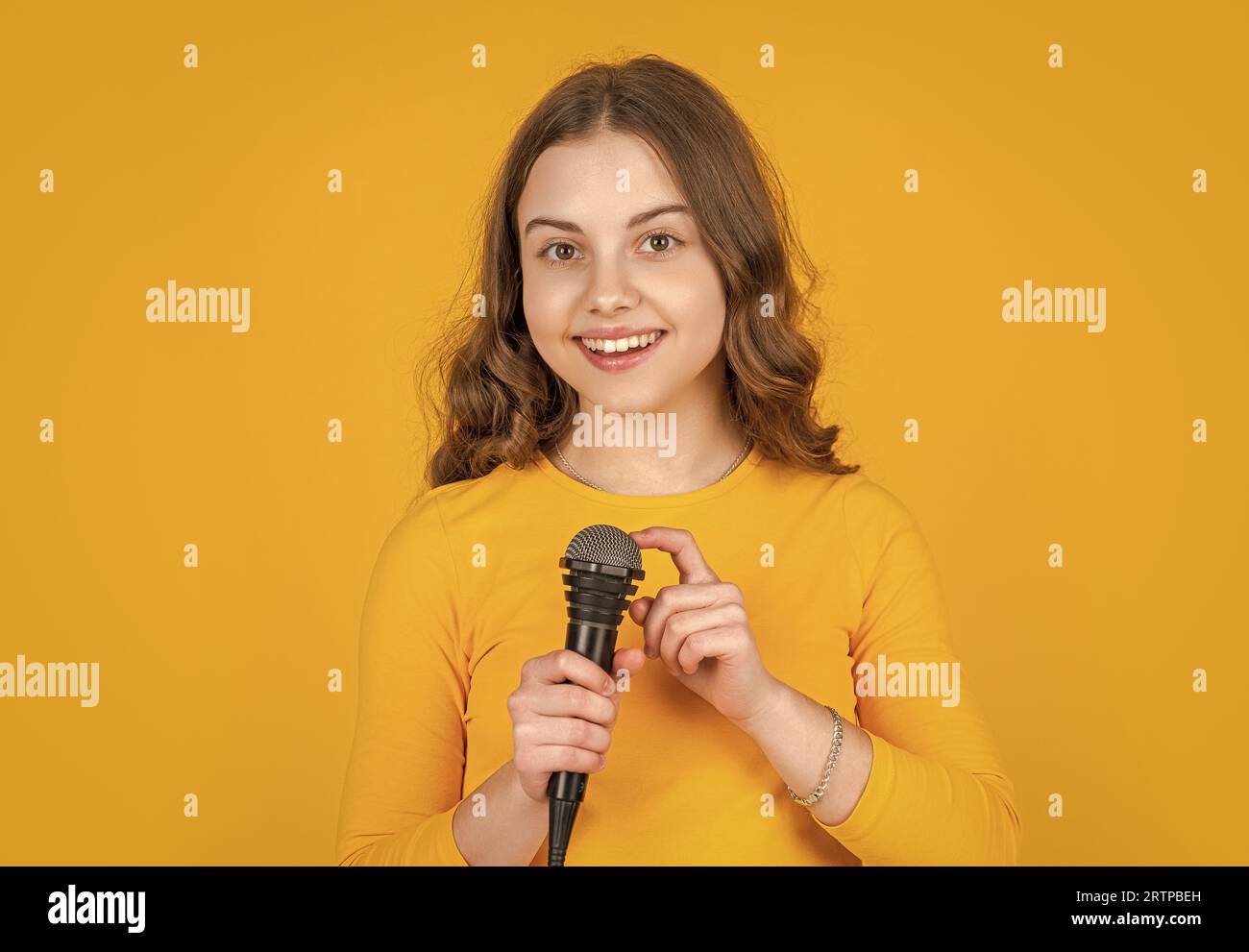 happy teen girl check microphone on yellow background Stock Photo - Alamy