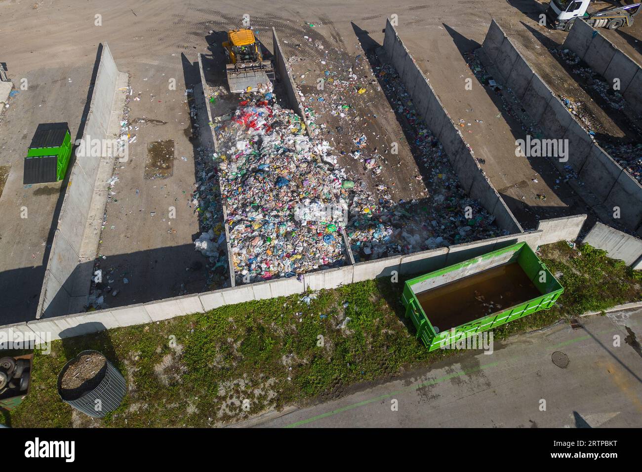 Wheeled loader operating on landfill site, carrying and dumping waste ...
