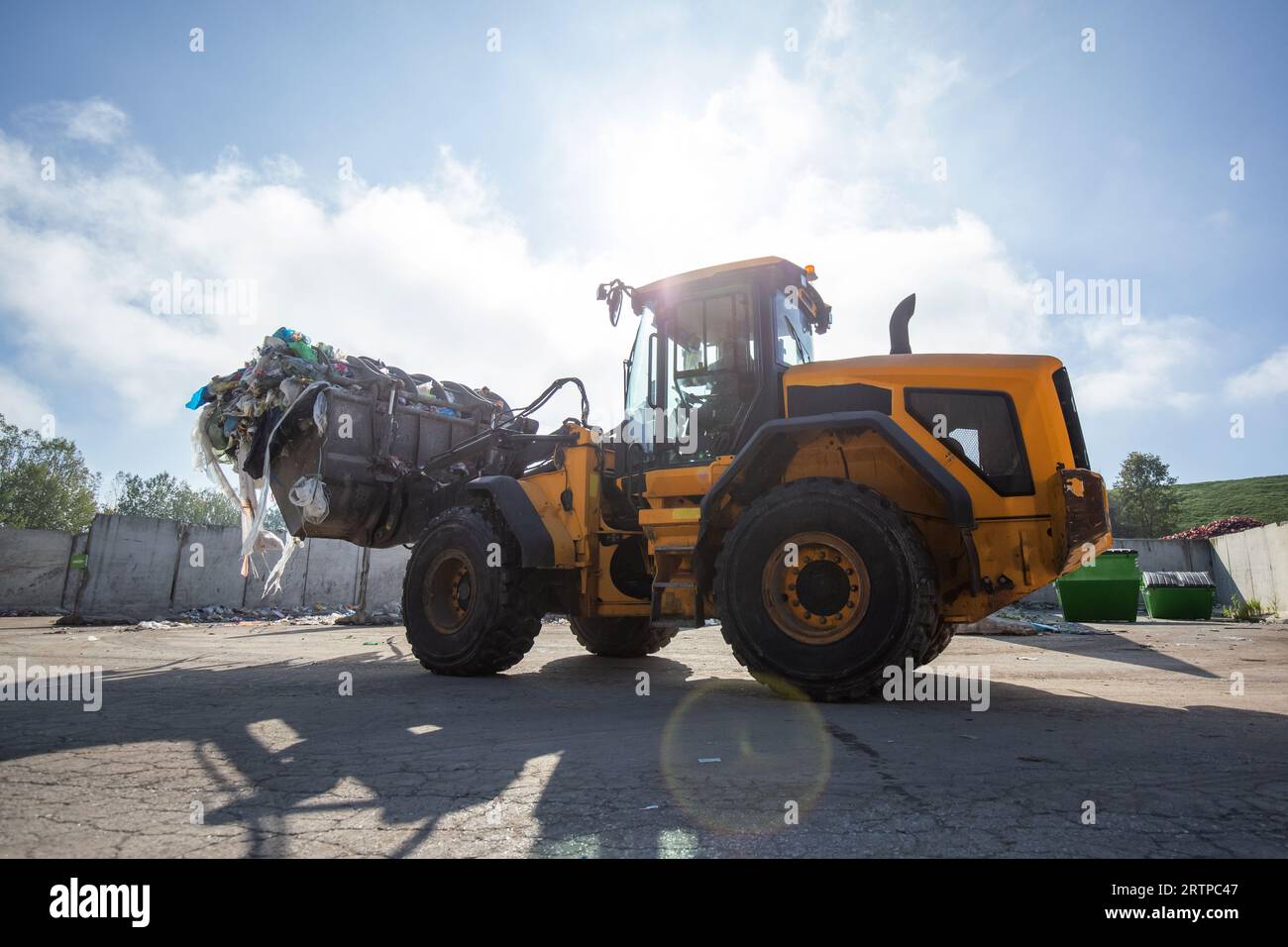 Yellow wheel loader, with lifted scrap grapple, moving along the ...
