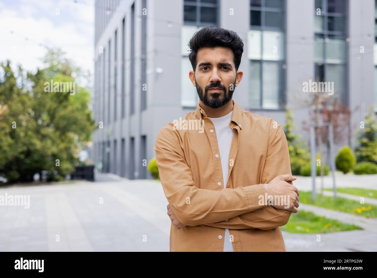 Serious thinking businessman programmer looking at camera with crossed ...