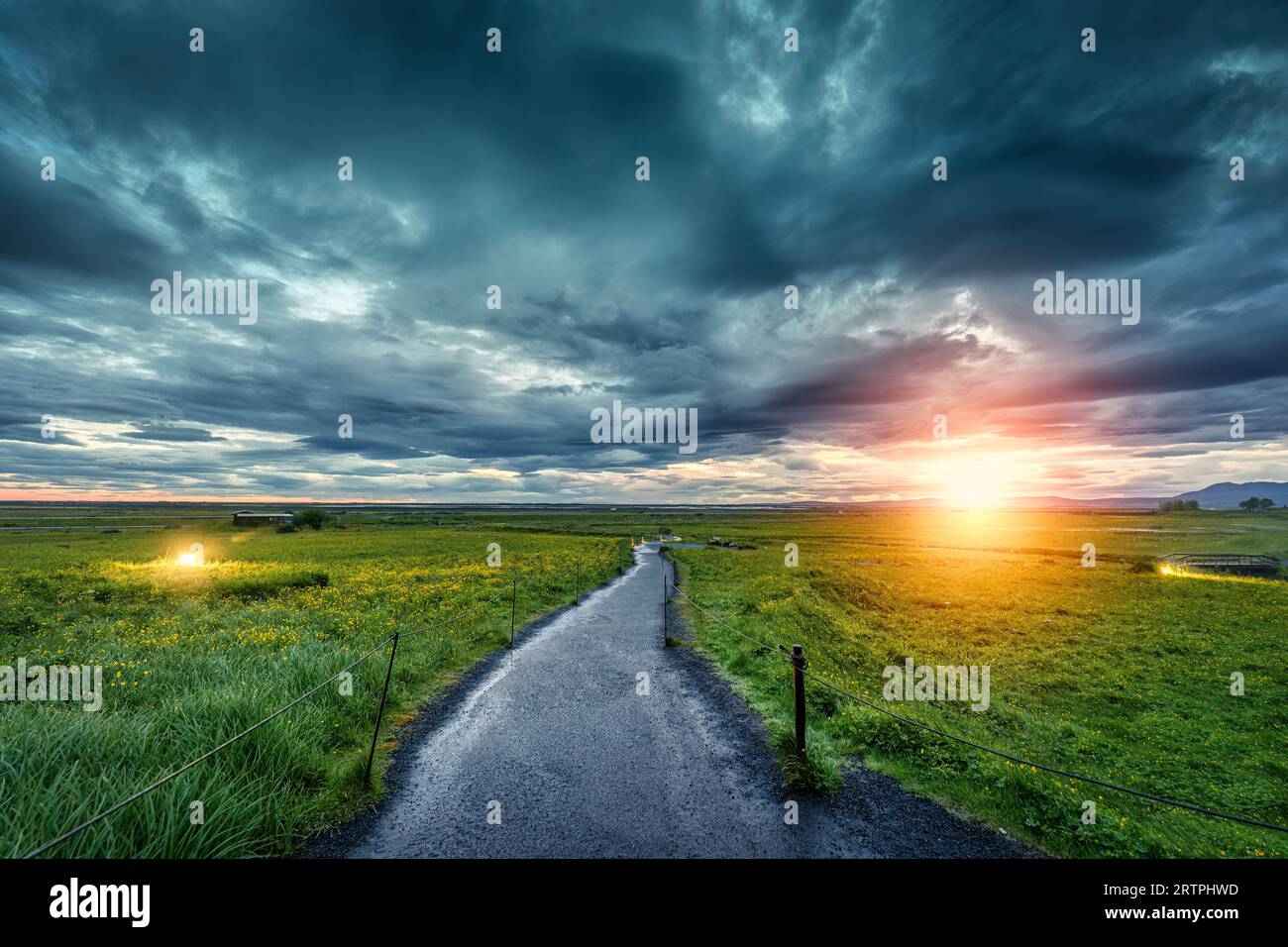 Dramatic view of pathway on agricultural field and moody sky in summer ...