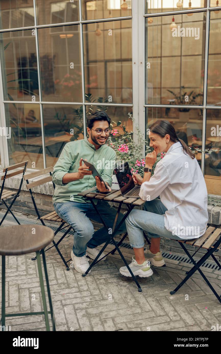 Cheerful business colleagues working outside of office on cafe terrace ...