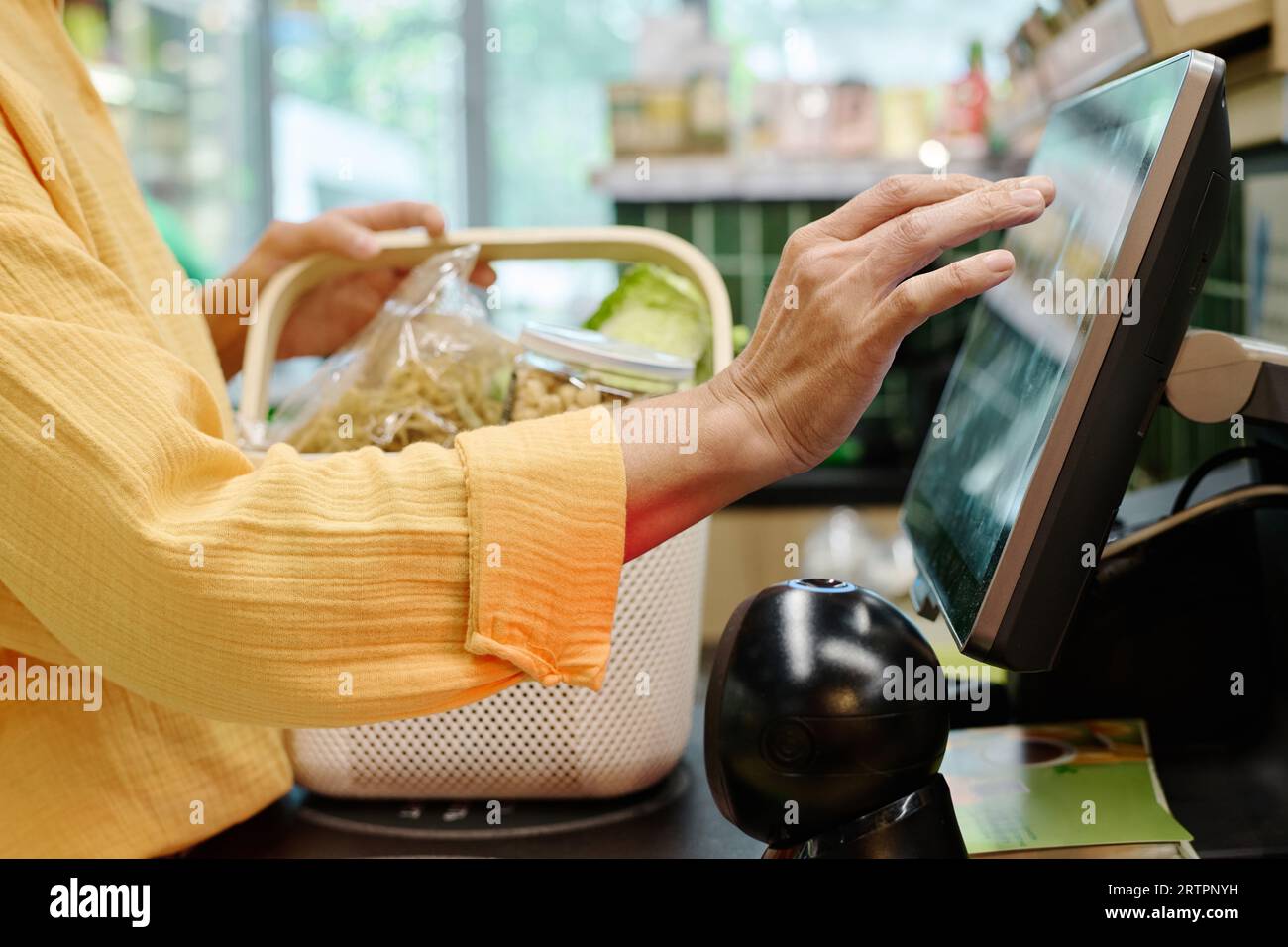 Close-up of customer using cash register to buy products herself in ...