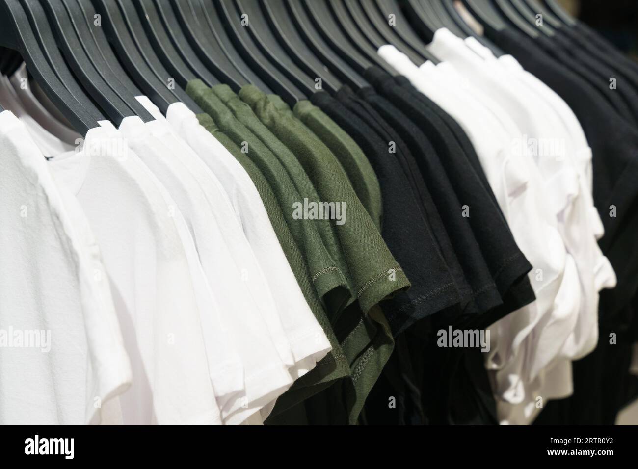 A collection of pastel-colored T-shirts hanging on a clothes rack on a ...
