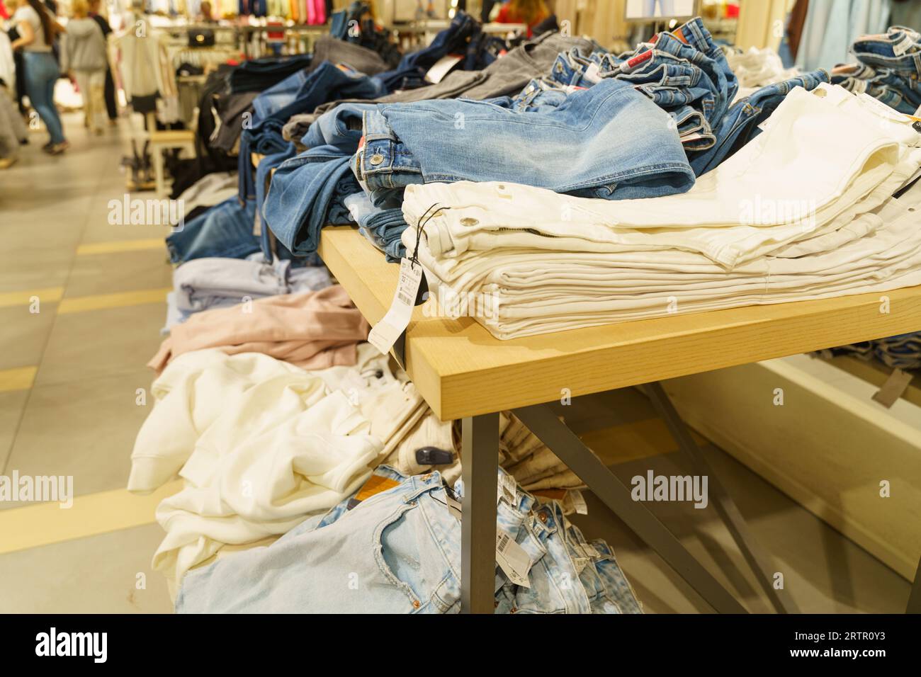 Women's jeans lie on the counter in a clothing store. Close-up ...