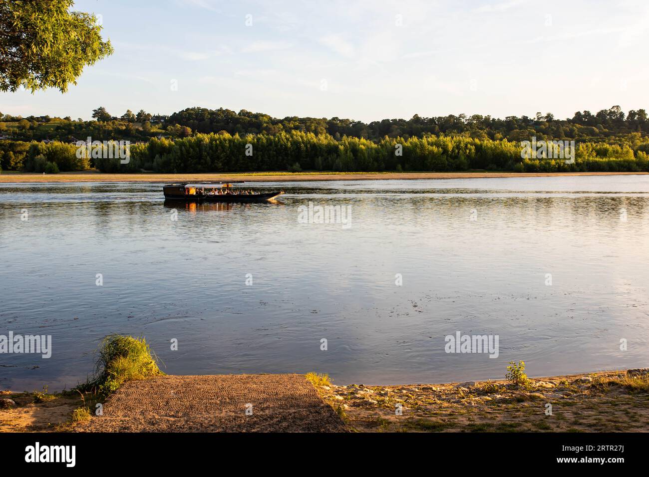 Loire river at sunset with a tourism boat, the traditional «toue» flat ...