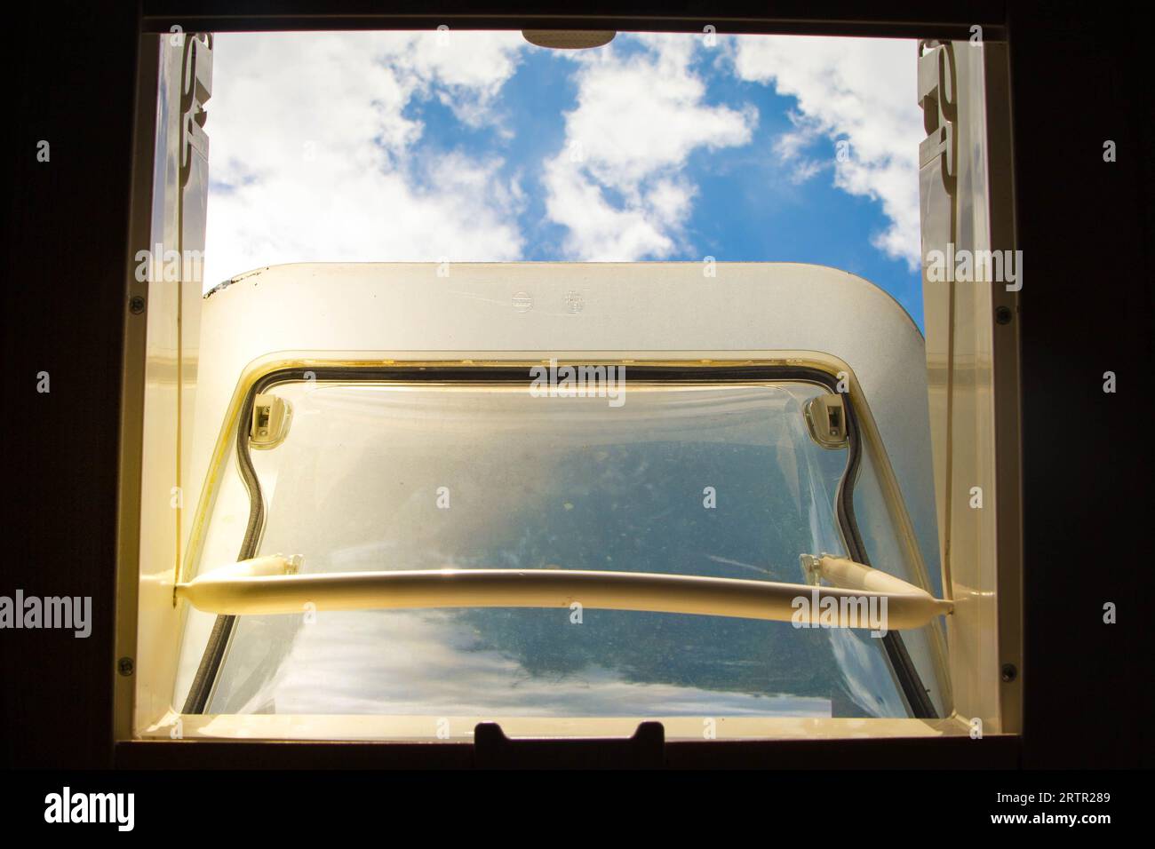 Camper van or motorhome flip out roof window open to see the blue sky ...