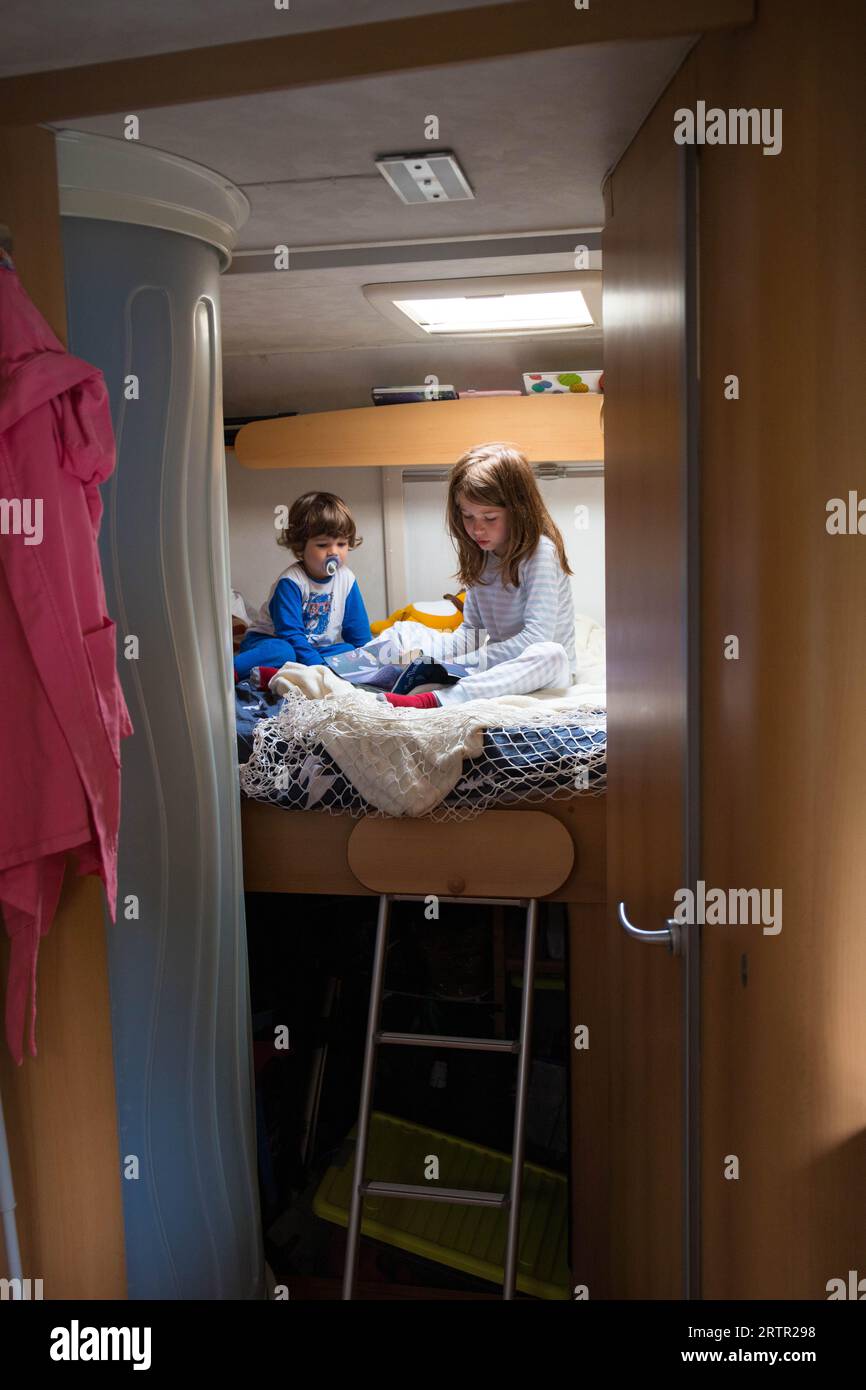 Two caucasian children, brother and sister, reading books in pajamas on ...