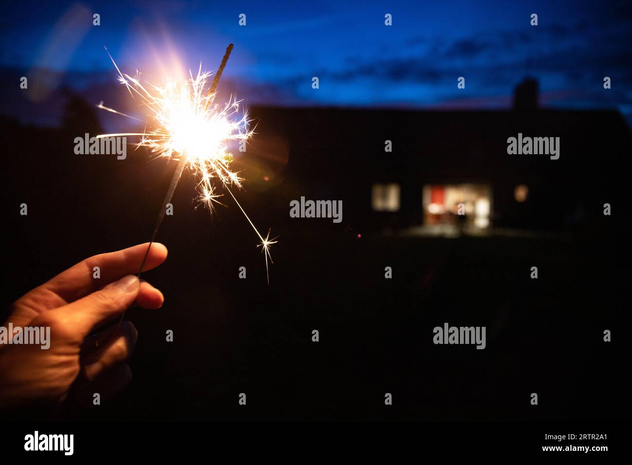 Hand holding a sparkler, or bengal fire stick, burning in outdoor ...