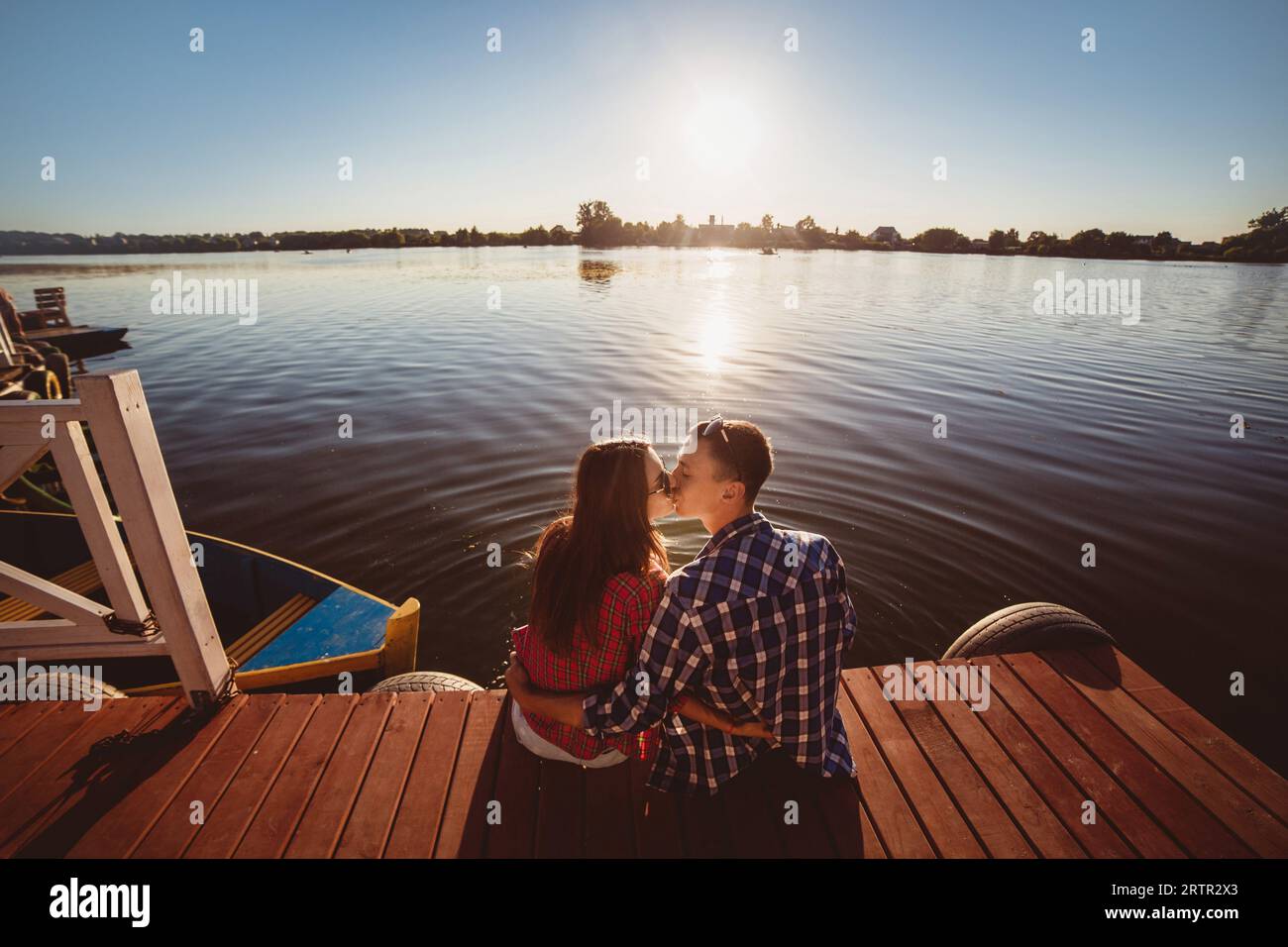 Romantic young couple in love sitting on pier.sunset on the lake Stock ...