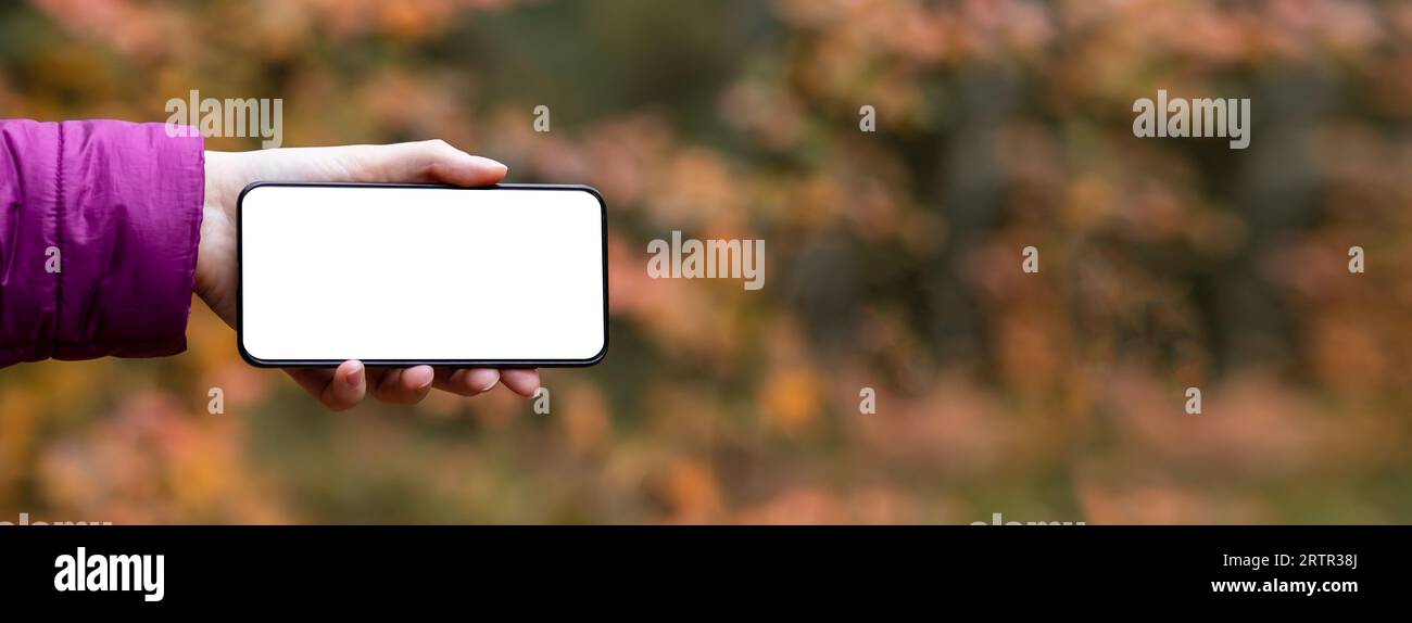 Hand holding mobile phone, horizontal screen mockup on autumn banner background Stock Photo - Alamy