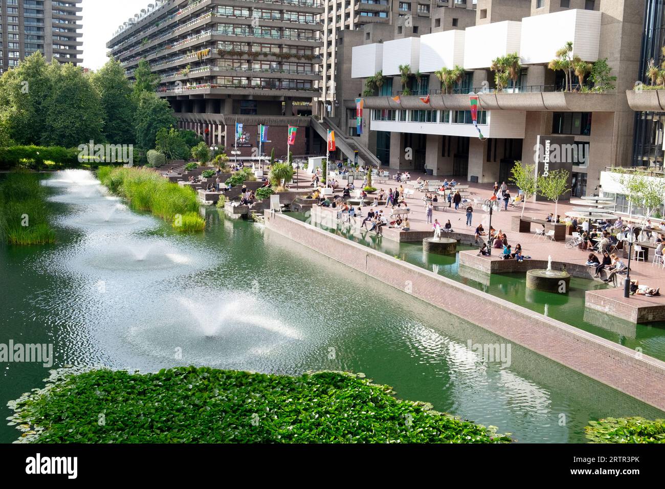 People relaxing on lakeside terrace by water fountains in summer ...