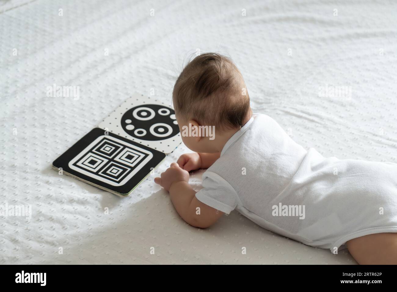 A baby looks at a black and white contrast educational book ...