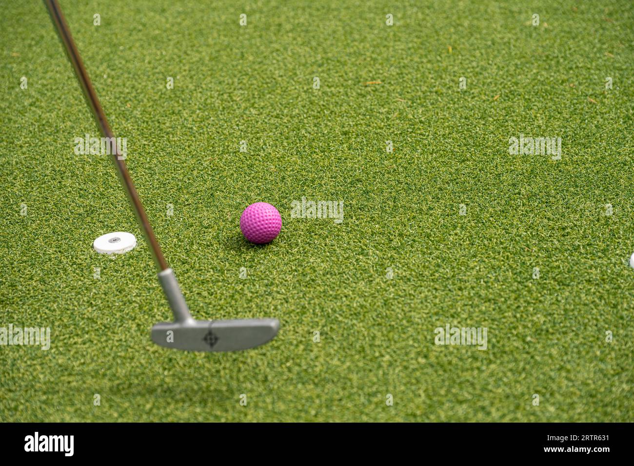 Miniature golf putter by blue ball and hole Stock Photo - Alamy