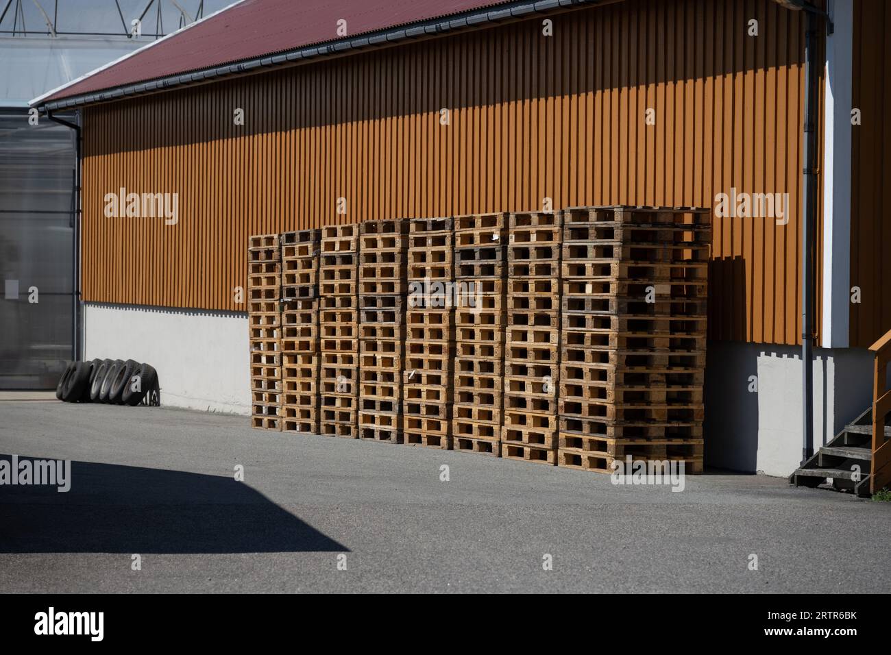 Stacks of wooden pallets by the side of a warehouse Stock Photo - Alamy