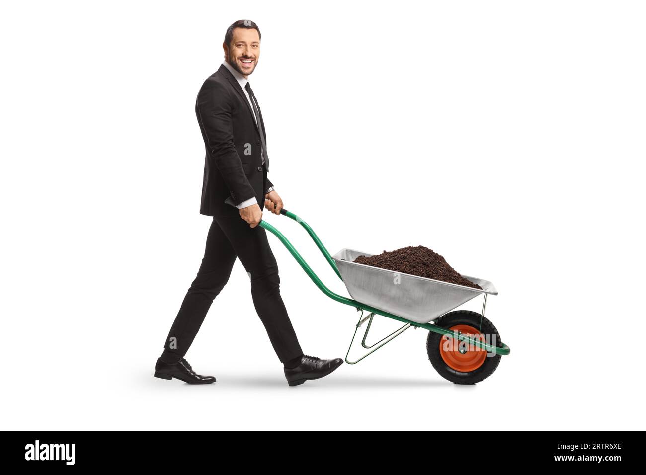Businessman pushing a wheelbarrow with earth isolated on white ...