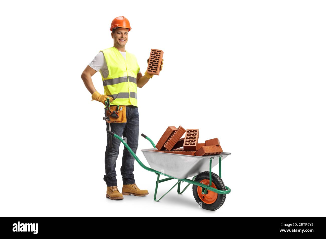 Construction worker holding a brick and standing behind a wheelbarrow ...