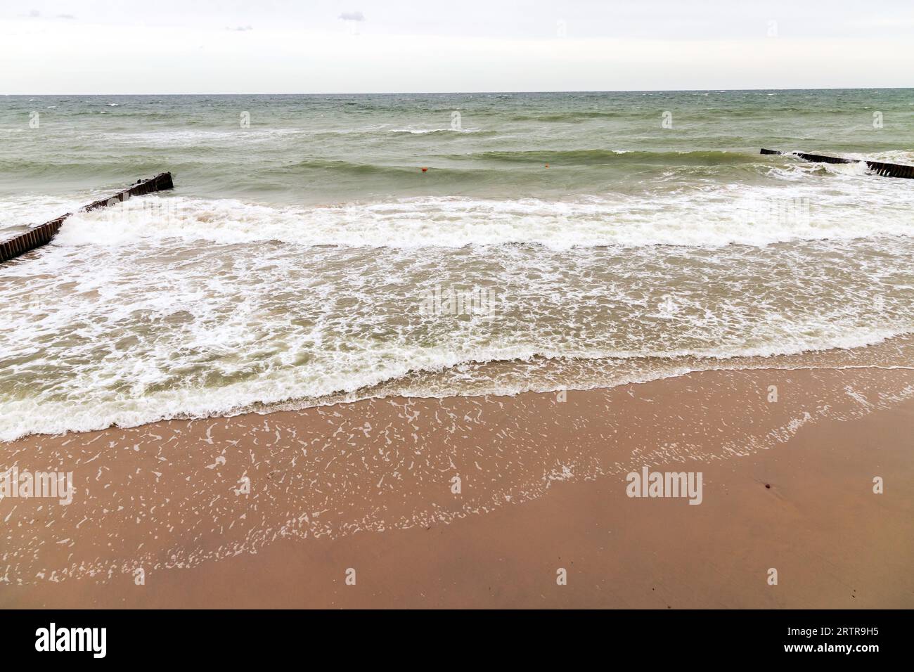 Seaside landscape with shore water and wooden breakwater structures ...