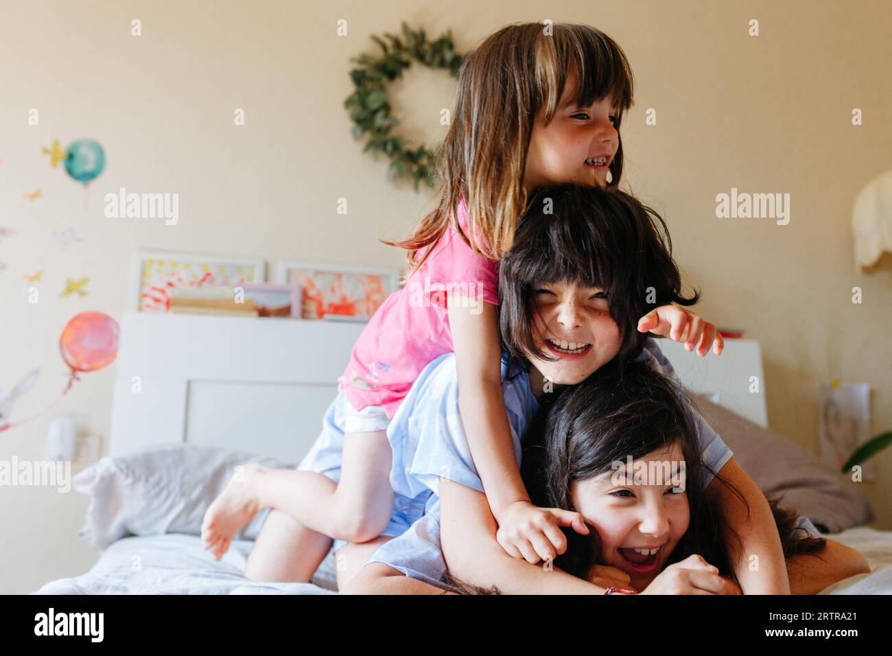 pyramid of three smiling children lying on each other on the bed Stock ...