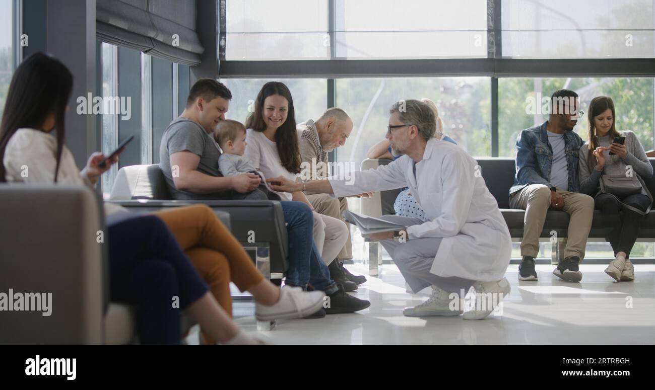 Diverse people sit on couches in clinic lobby area, wait for doctors ...