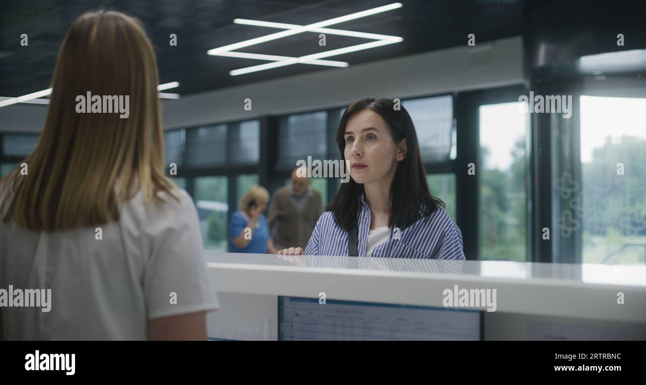 Adult woman stands near reception desk in clinic lobby area and comes ...