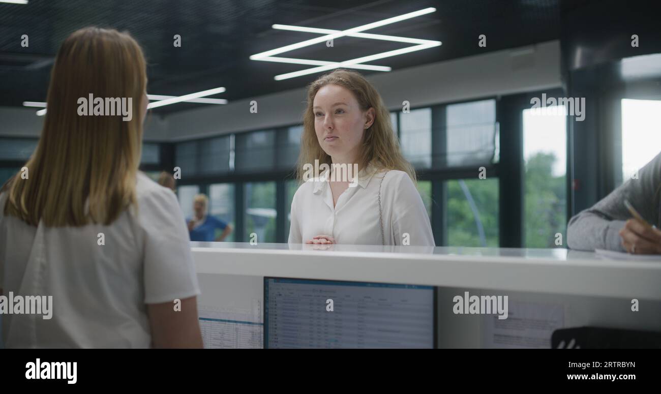 Adult woman stands near reception desk in clinic lobby area and makes ...