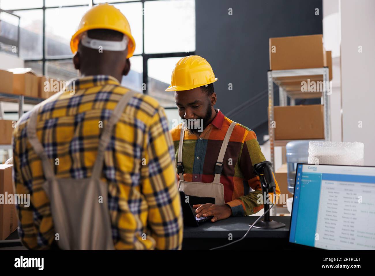 African american warehouse operators checking delivery schedule on ...
