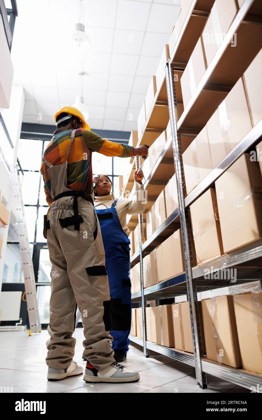 African american warehouse worker scanning parcel for logistics manager ...