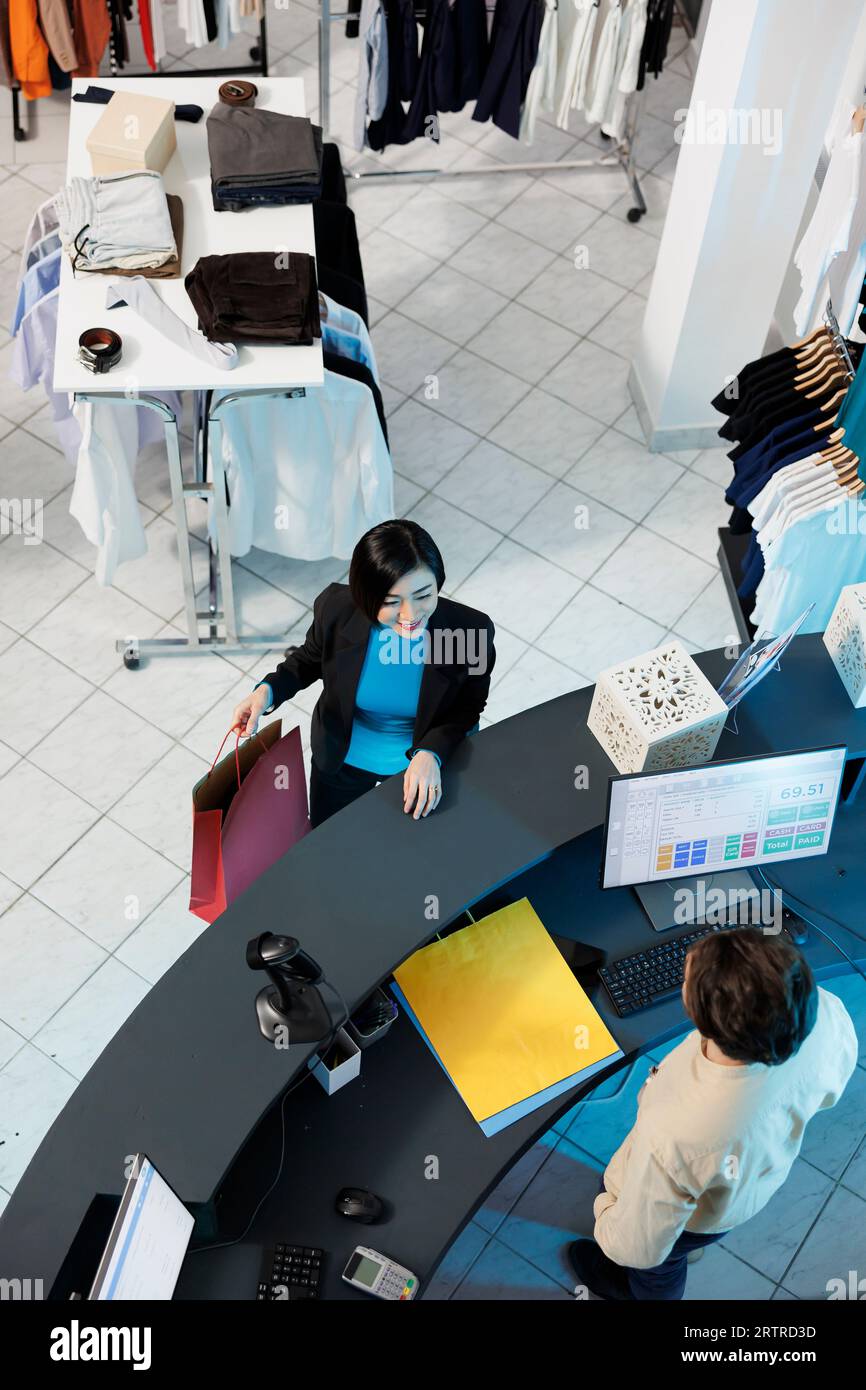 Smiling asian woman talking with cashier while making purchase at ...