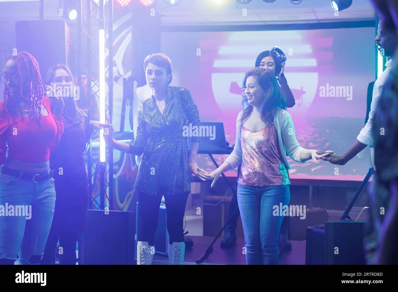 Young clubbers girlfriends holding hands and dancing together in ...