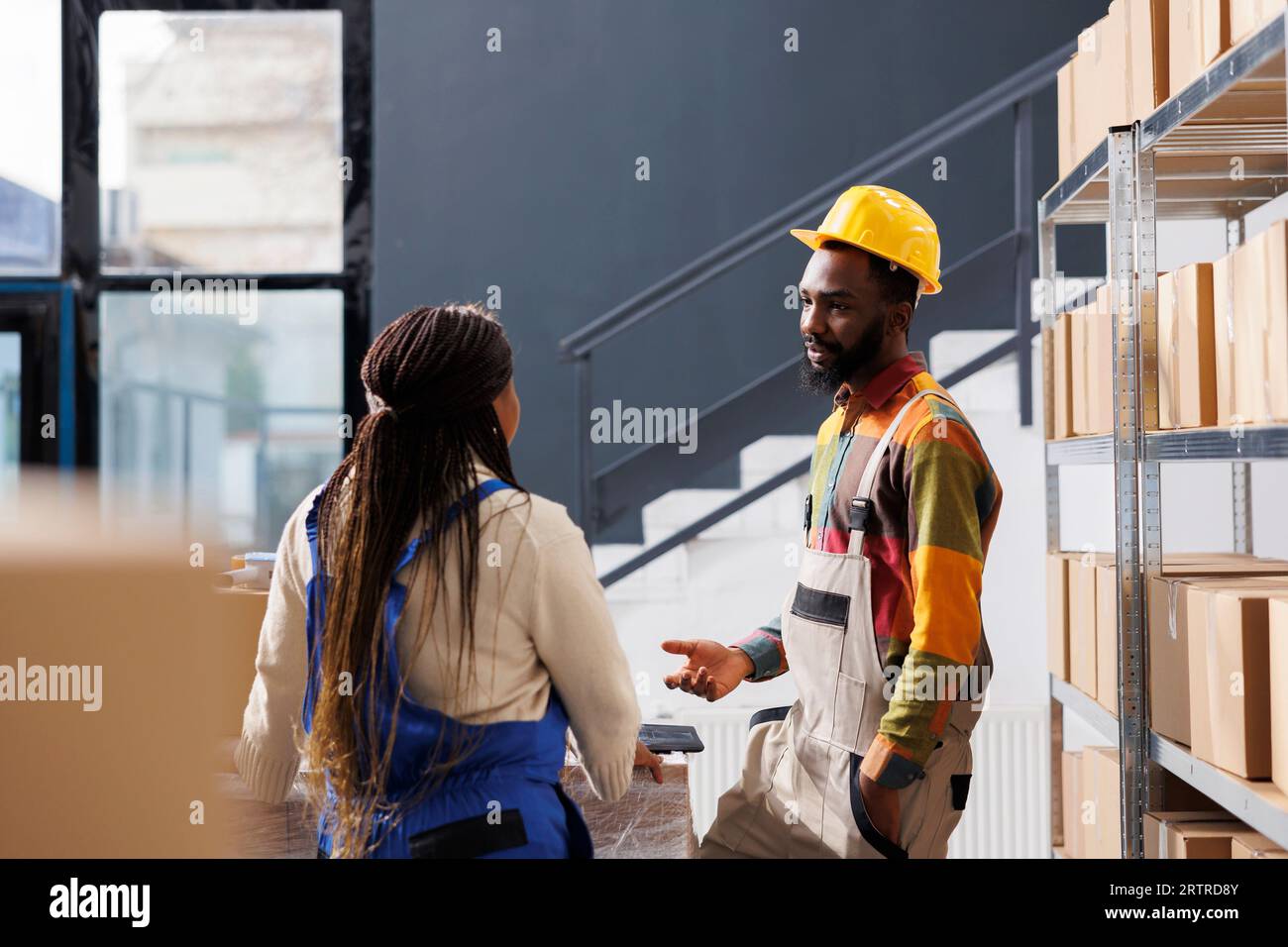 African american warehouse worker explaining colleague parcel packing instruction in stockroom ...