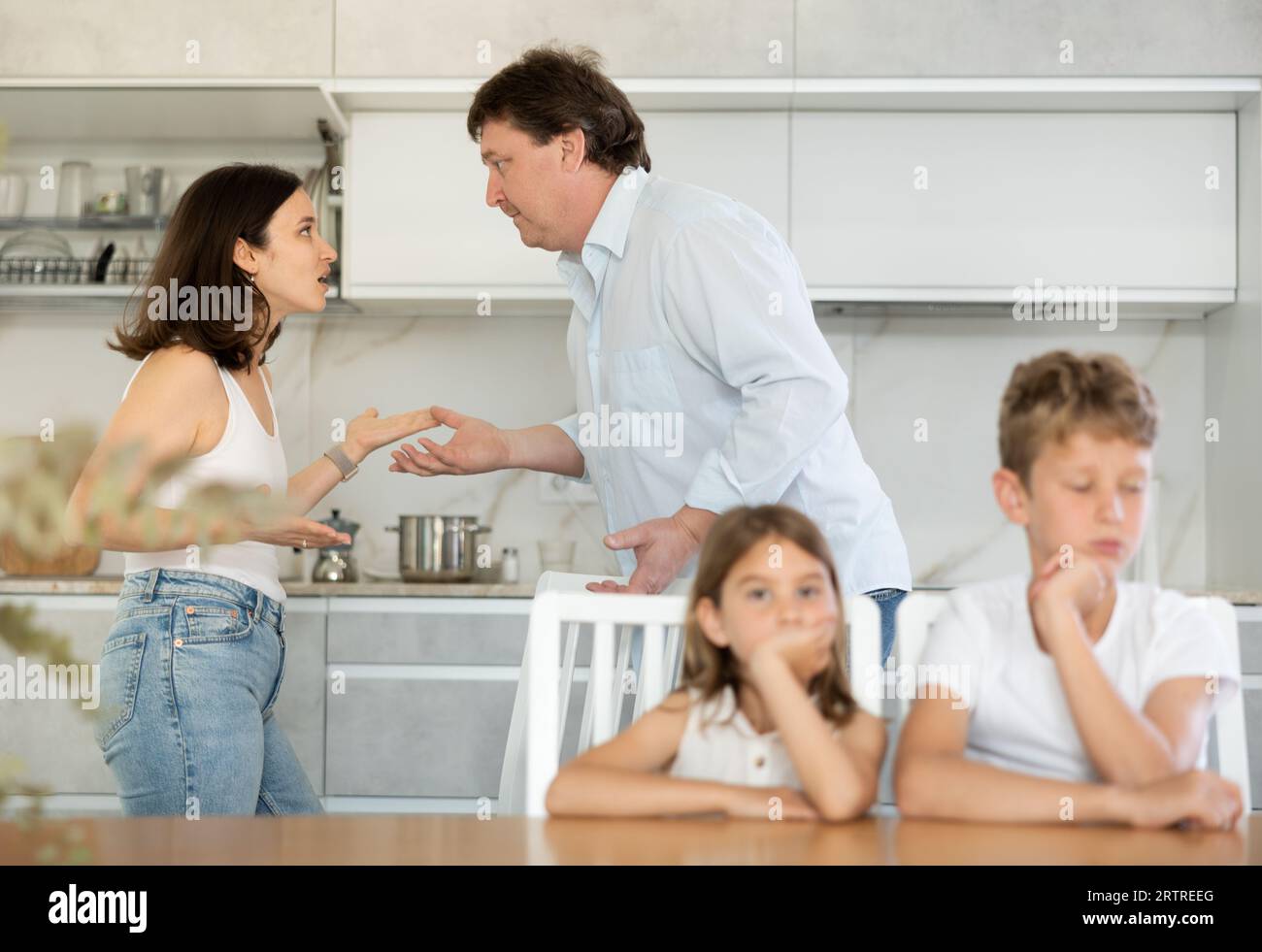 Brother and sister sit at table during quarrel between parents Stock ...