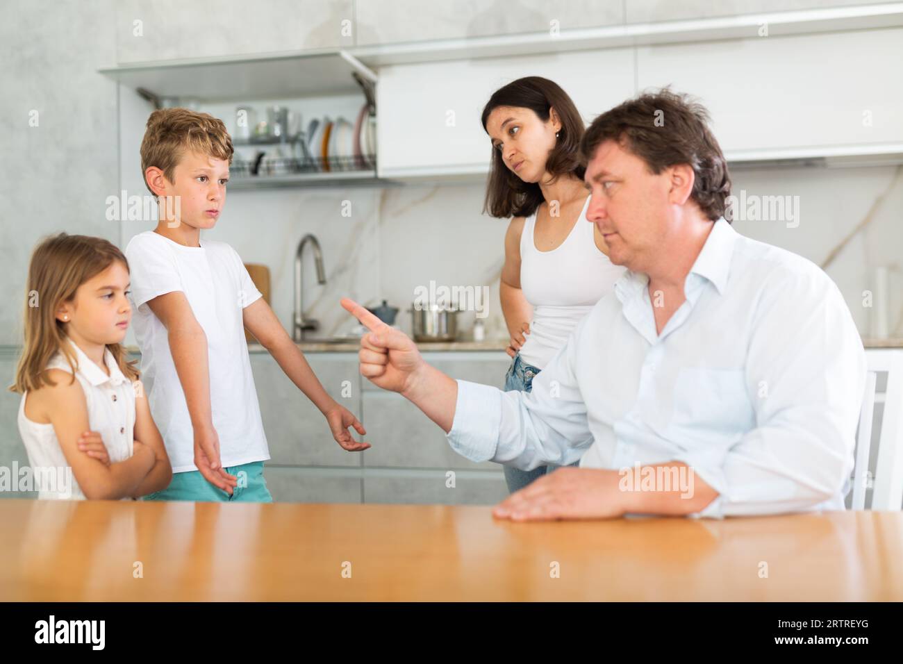 Angry parents scolding two children standing in front of them Stock ...