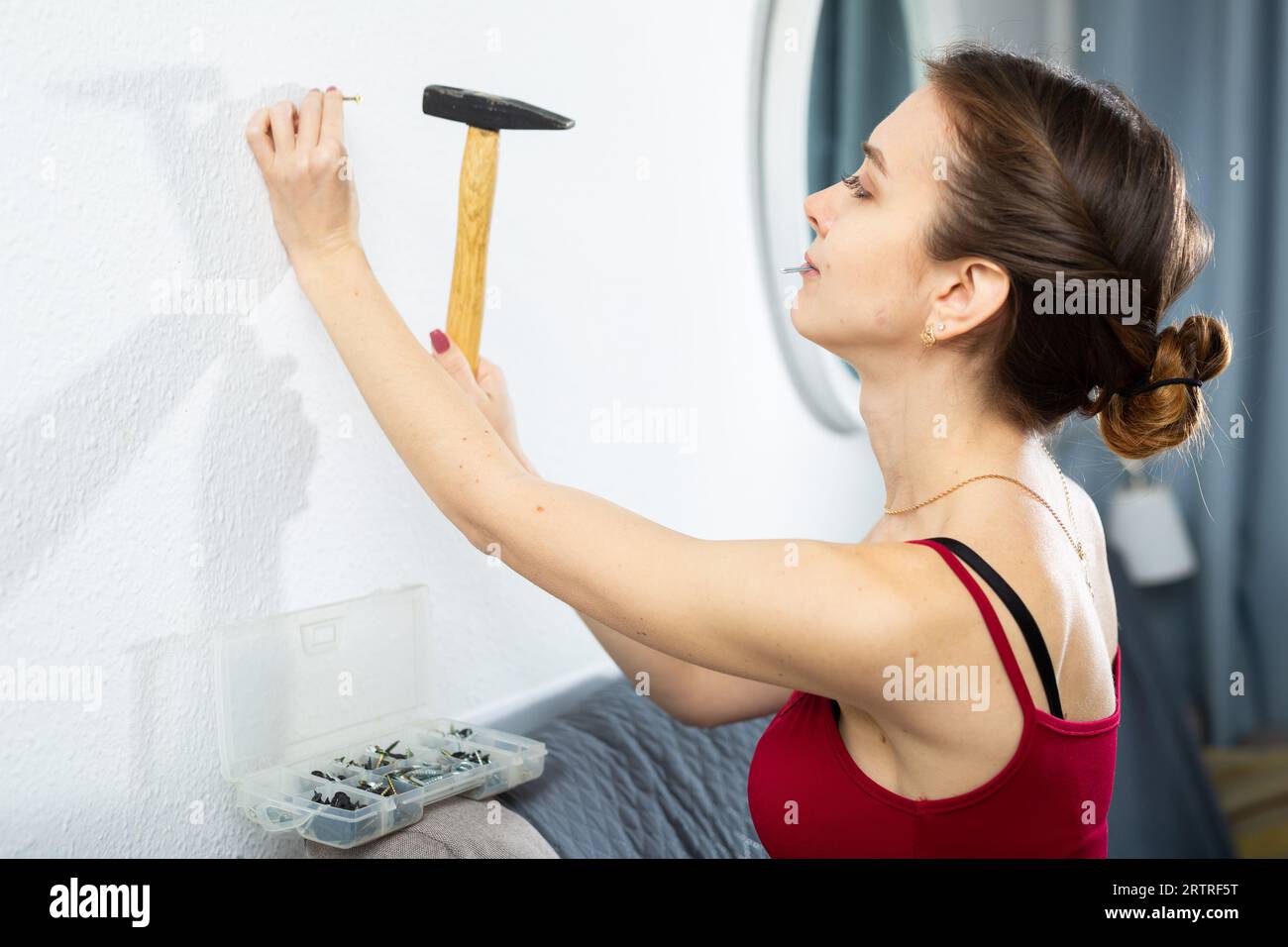 Young woman hammering a nail into the wall with hammer Stock Photo - Alamy