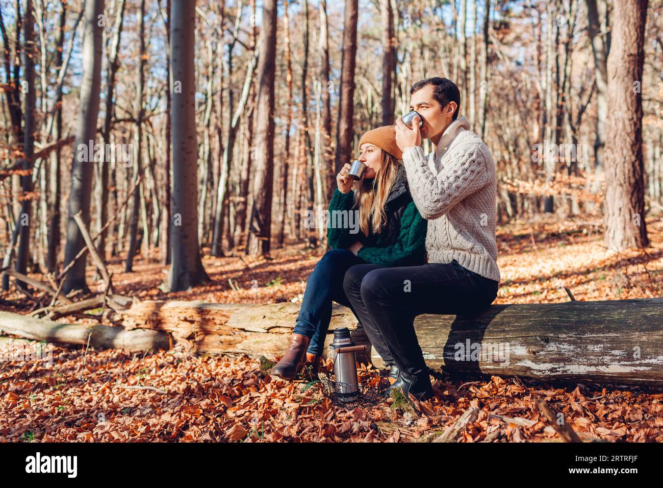 Portrait of young loving couple drinking tea relaxing in fall forest ...
