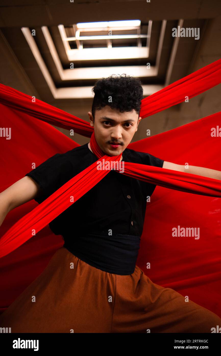 an Asian man in a black shirt is strangled with a red cloth while ...
