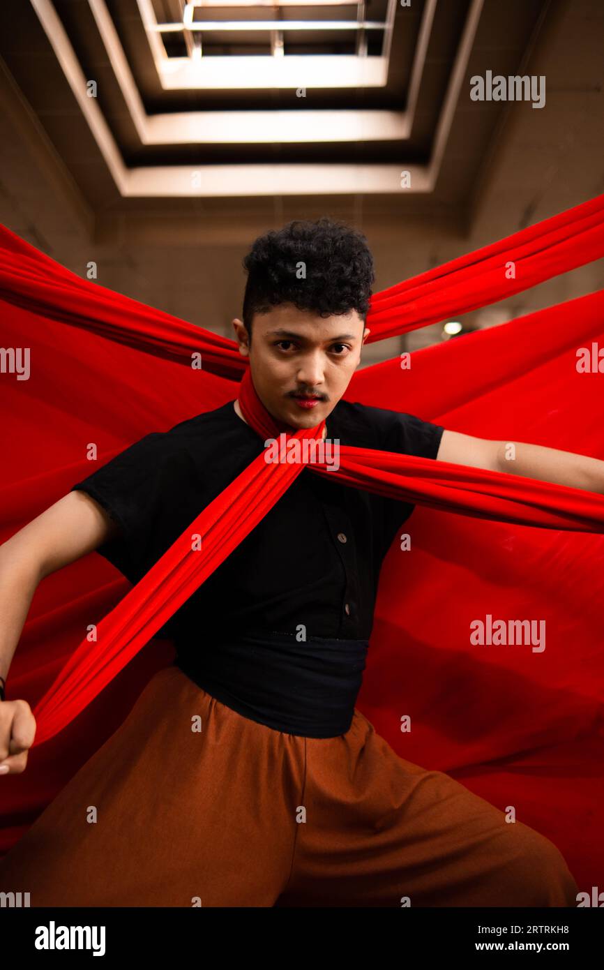 an Asian man in a black shirt is strangled with a red cloth while ...