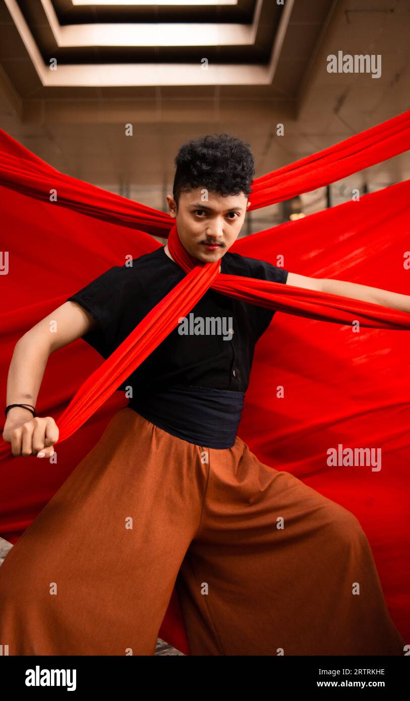 an Asian man in a black shirt is strangled with a red cloth while ...