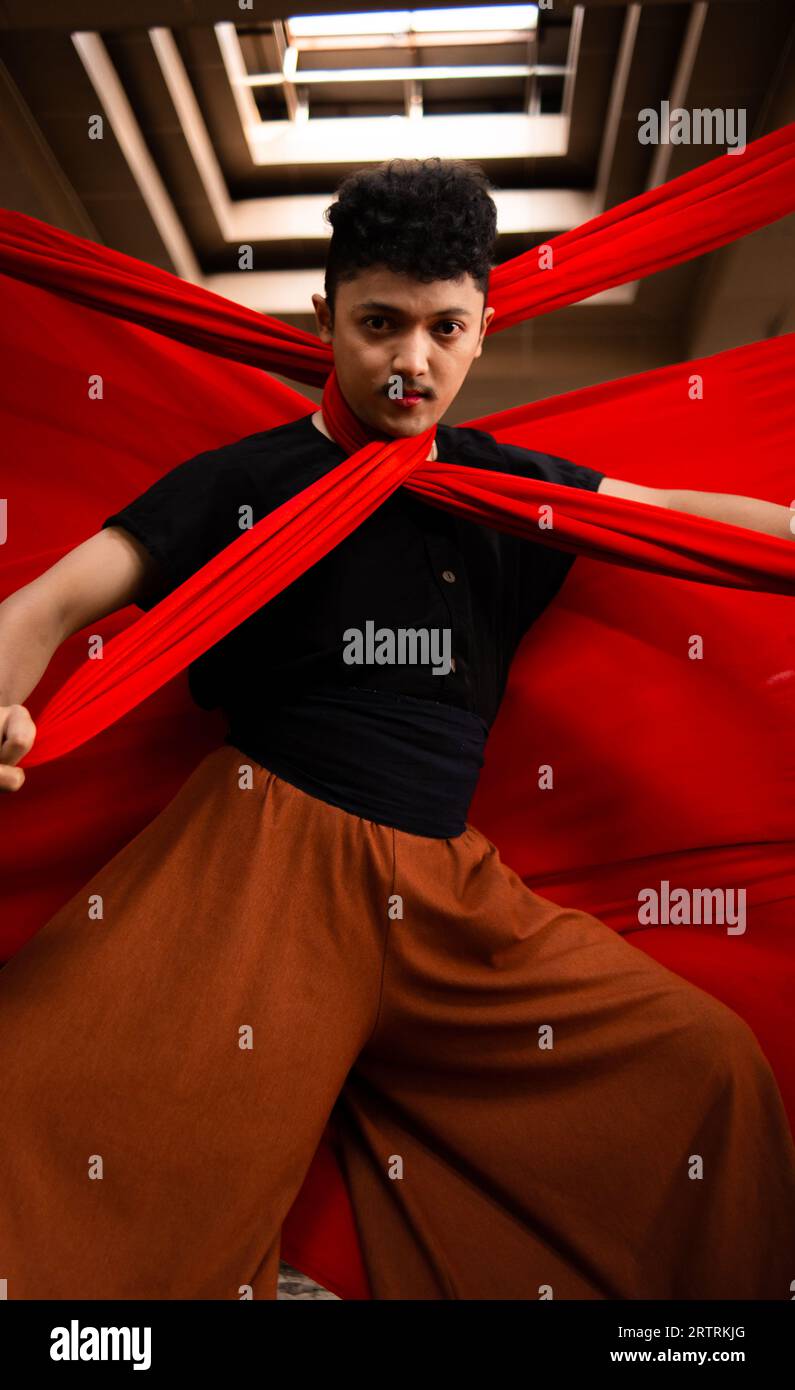 an Asian man in a black shirt is strangled with a red cloth while ...