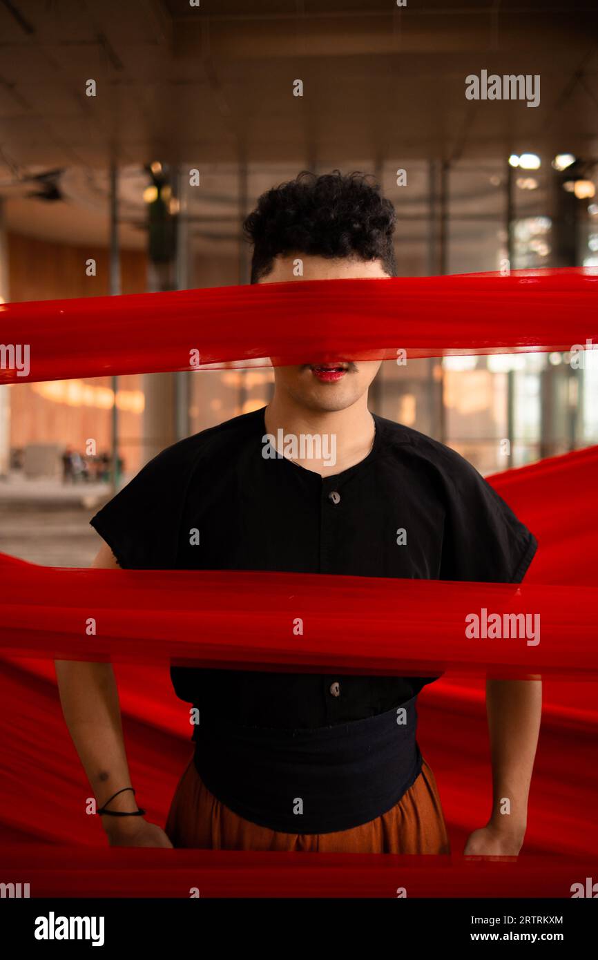 an Asian man standing proudly among the red cloth that dangles in an ...