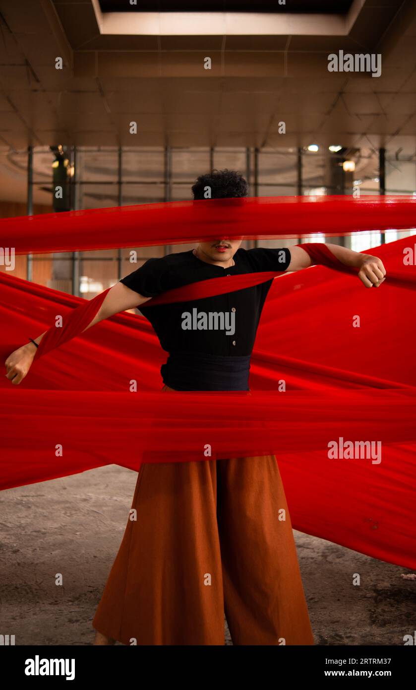an Asian man standing proudly among the red cloth that dangles in an ...