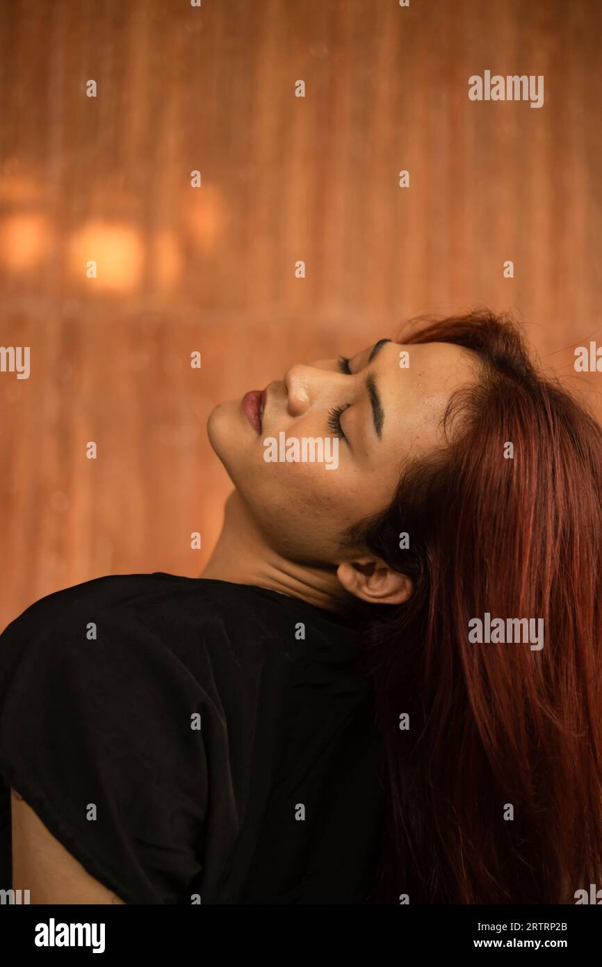 an Asian man sleeping on a brown table with long hair hanging down ...