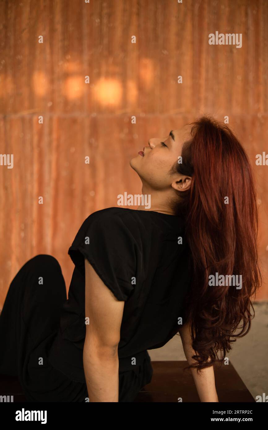 an Asian man sleeping on a brown table with long hair hanging down ...
