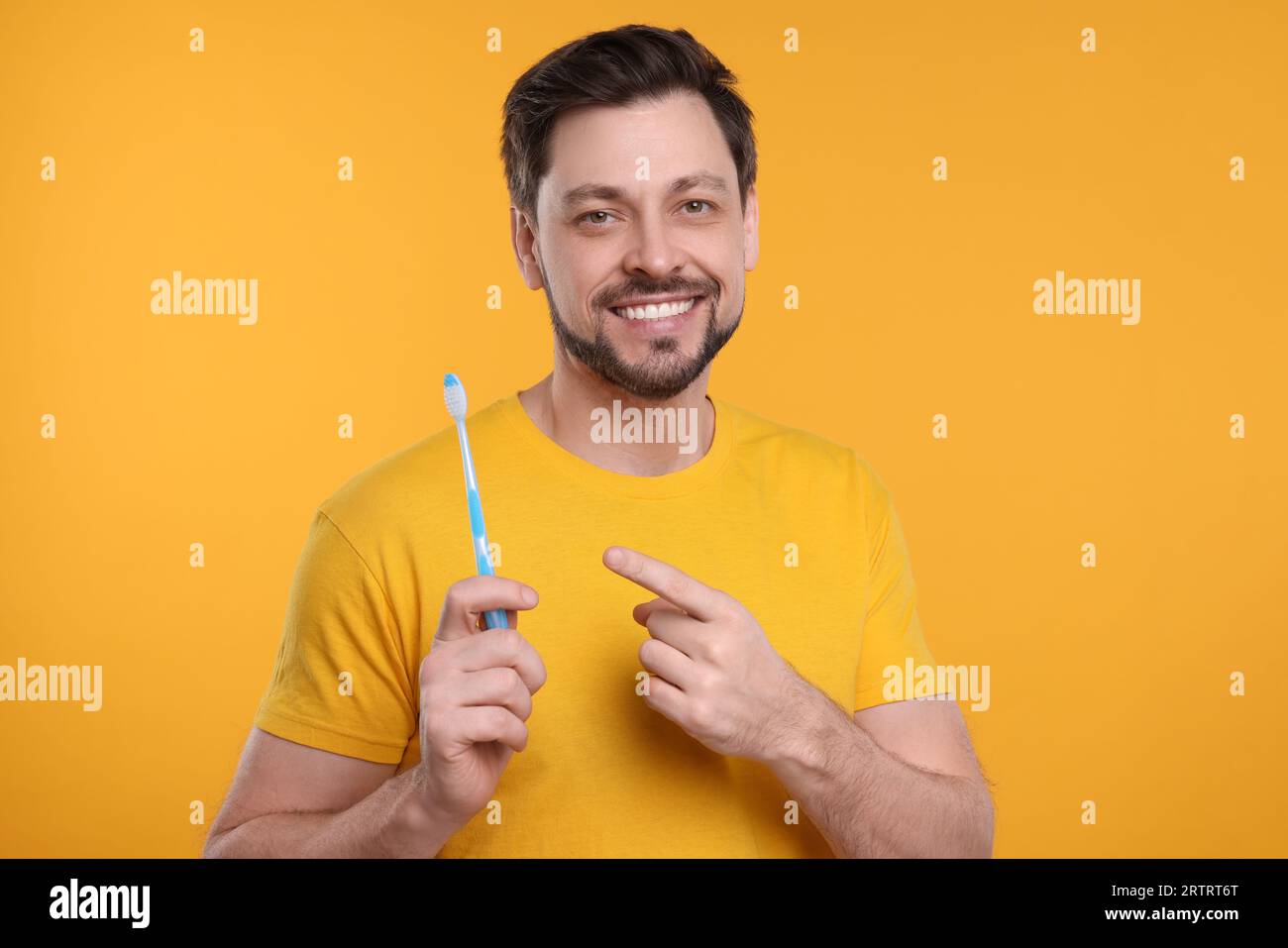 Happy man holding plastic toothbrush on yellow background. Mouth ...