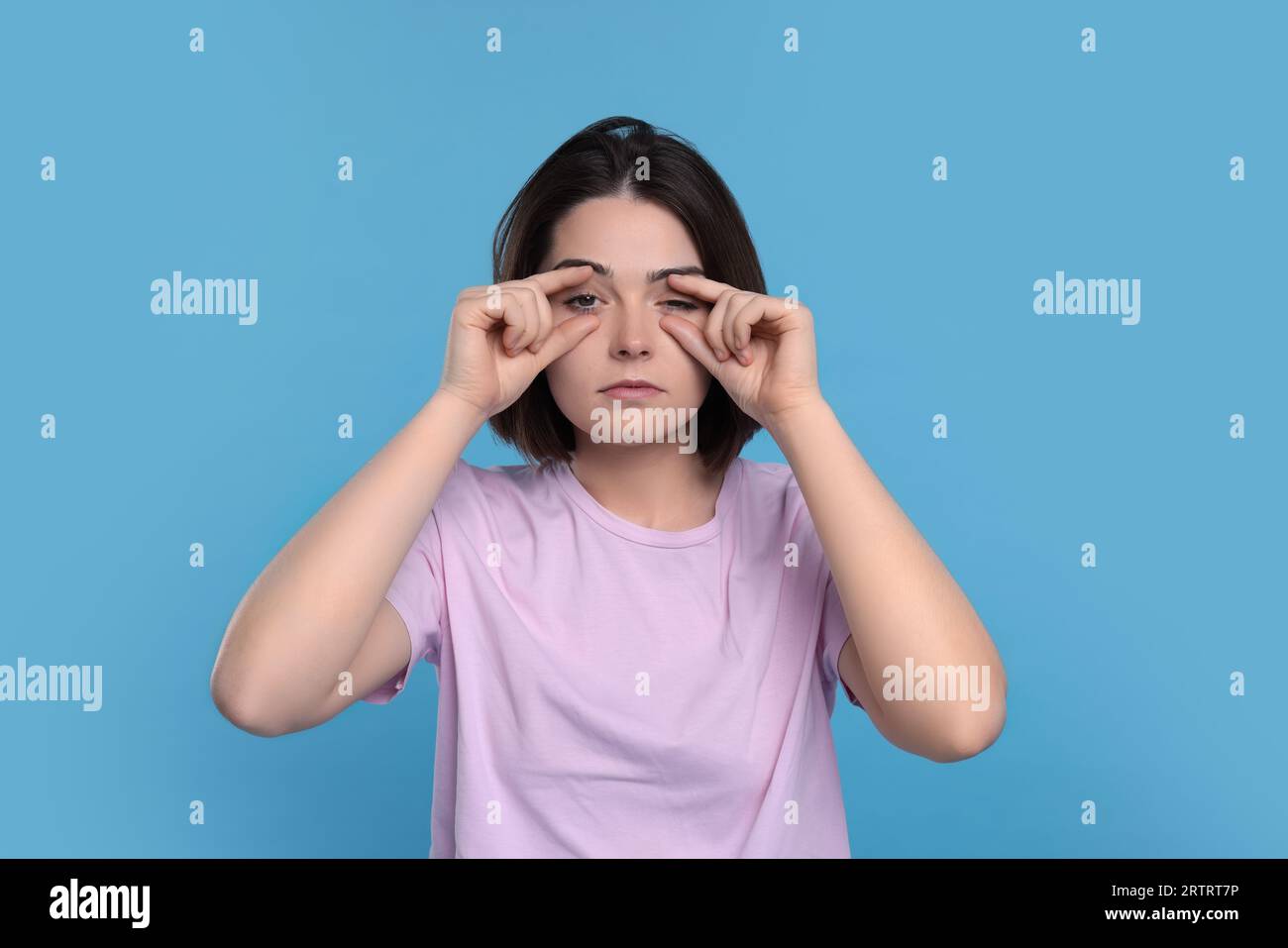 Sleepy young woman on light blue background. Insomnia problem Stock ...