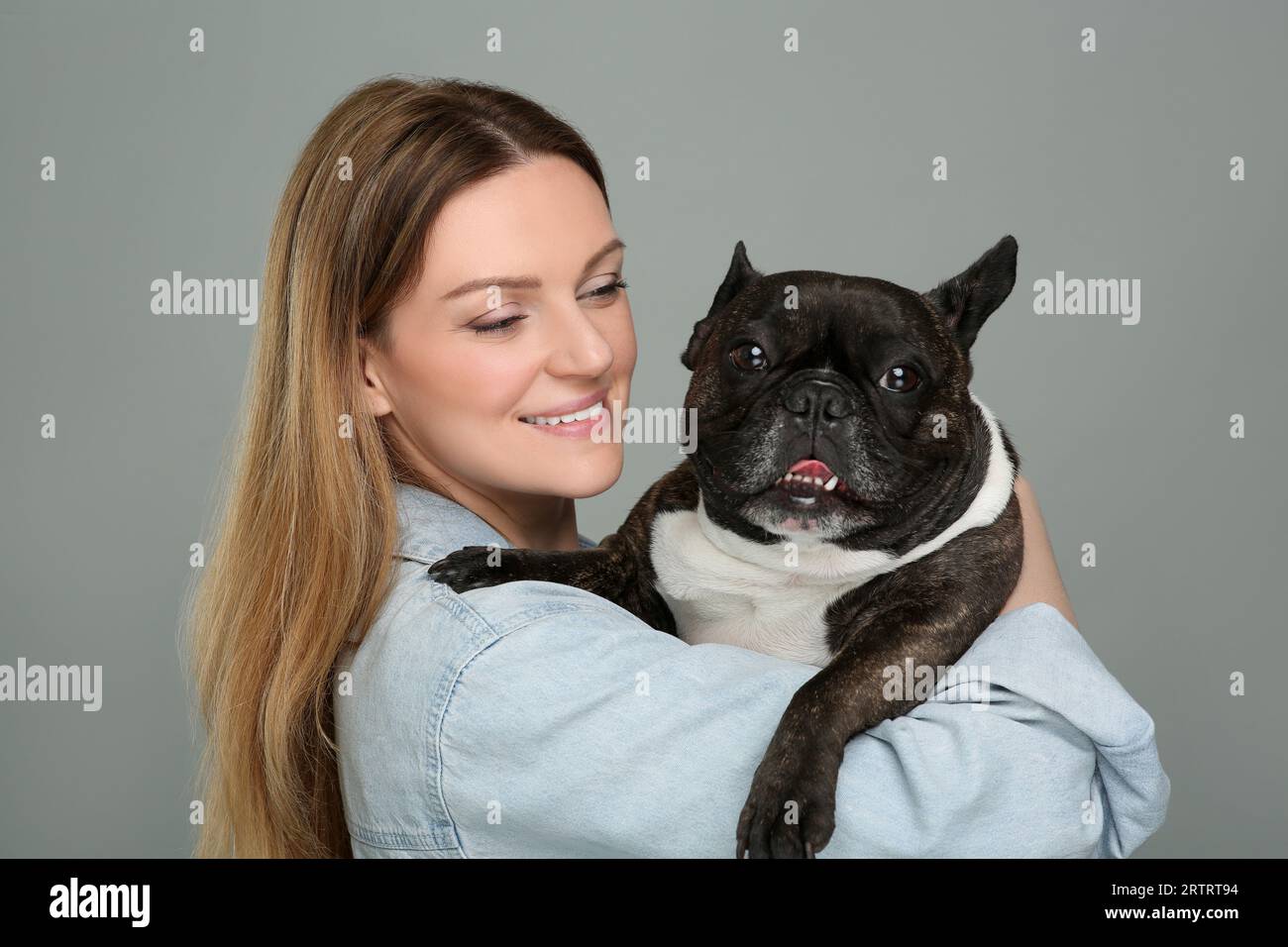 Happy woman hugging cute French Bulldog on grey background Stock Photo ...