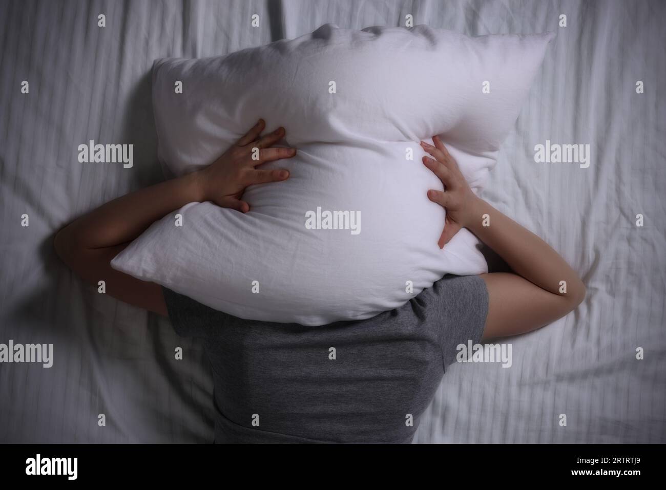 Woman covering her head with pillow on bed, top view. Insomnia problem ...